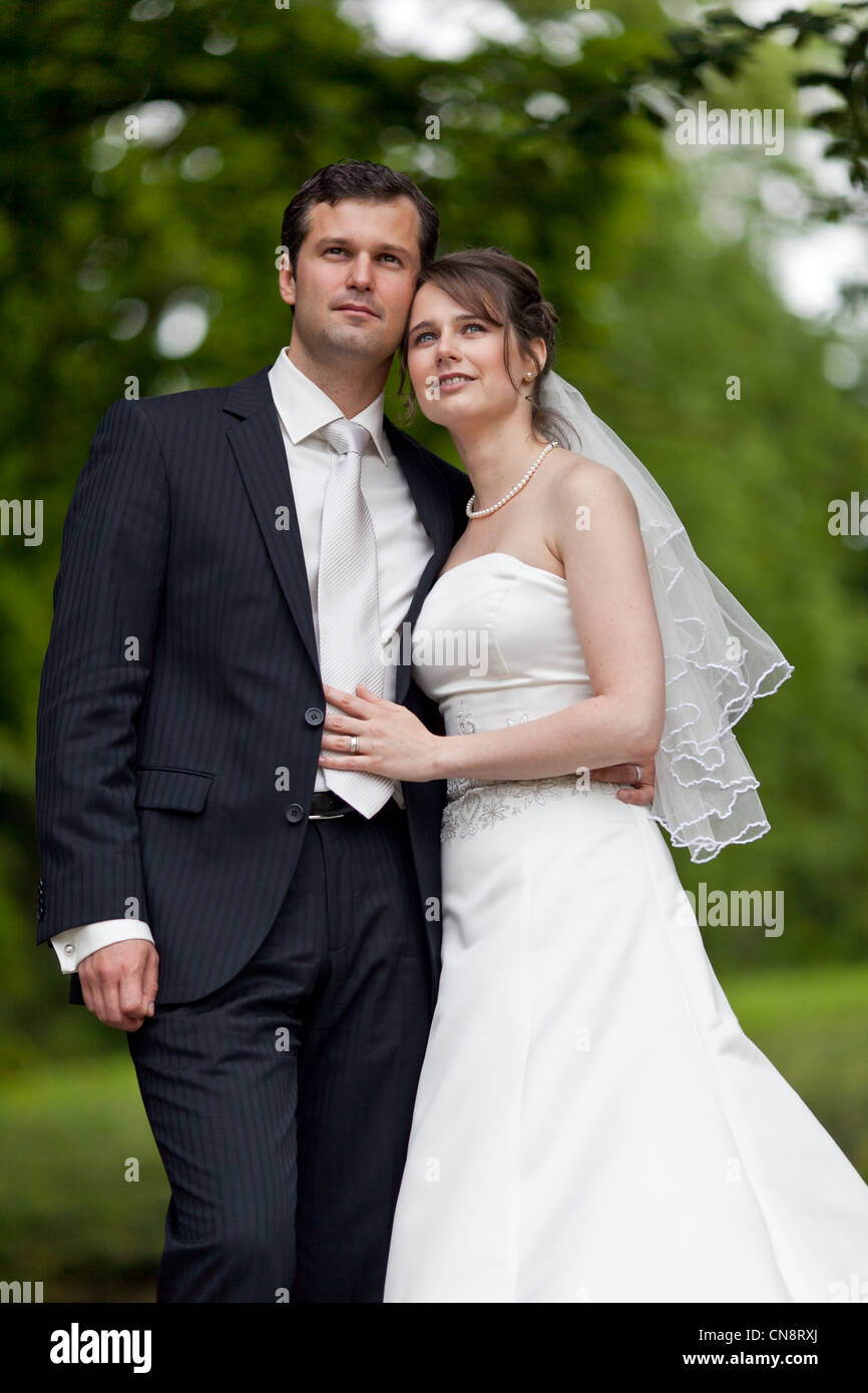 young wedding couple - freshly wed groom and bride posing outdoors on ...