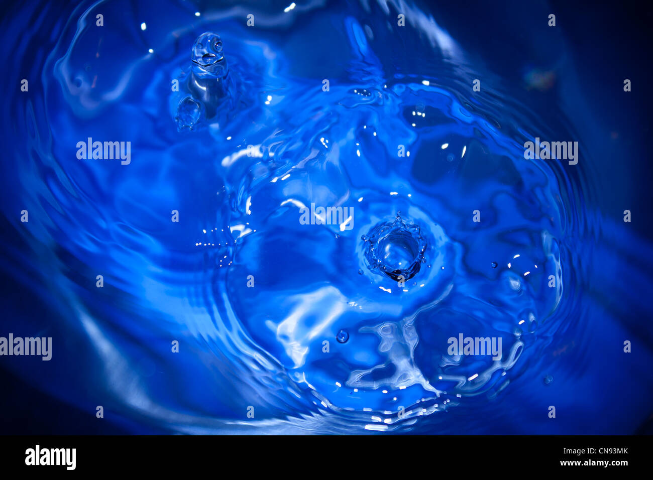 Water dripping into vivid blue water creating ripples Stock Photo - Alamy