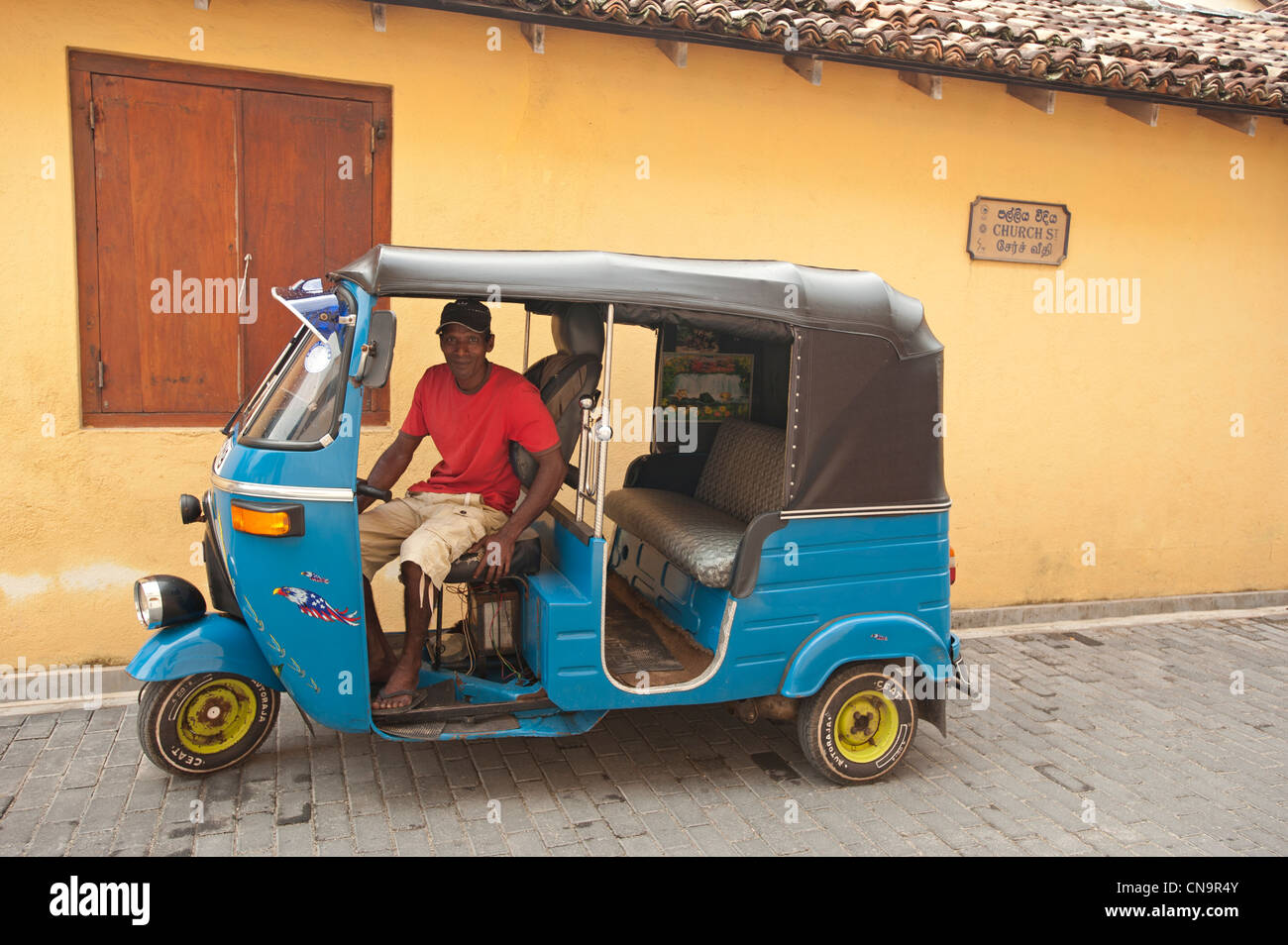 Blue three wheeled rickshaw and driver smile in the Galle Fort Sri ...
