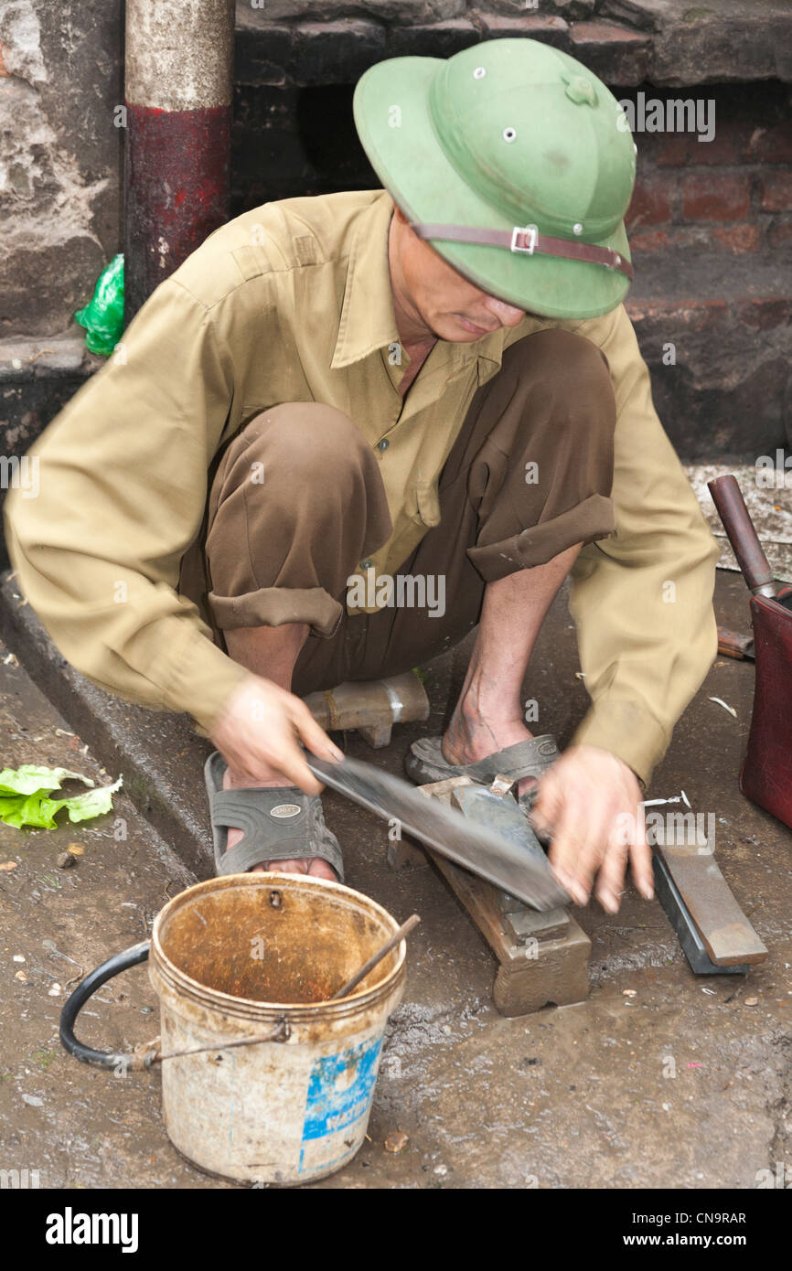 Man using a whetstone to sharpen a blade in the old town, Hanoi ...