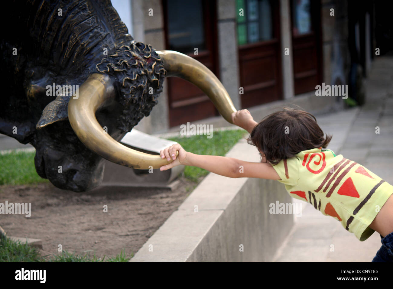 A BULL`S HEAD (SCULPTURE) BEING STOPPED BY A SMALL KID PUSHING THE BULL ...