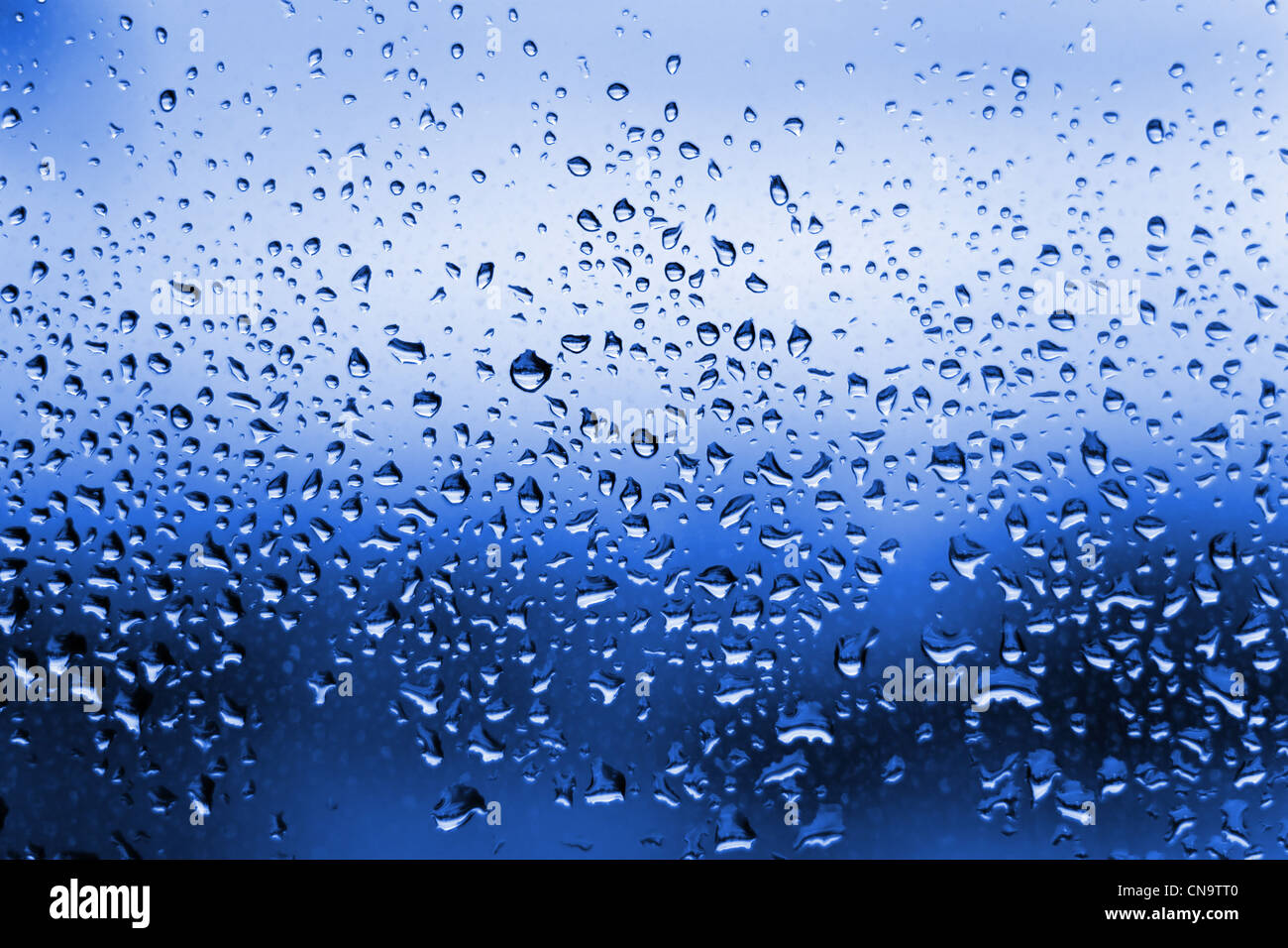 A close up shot of blue water droplets on a glass window pane Stock Photo - Alamy