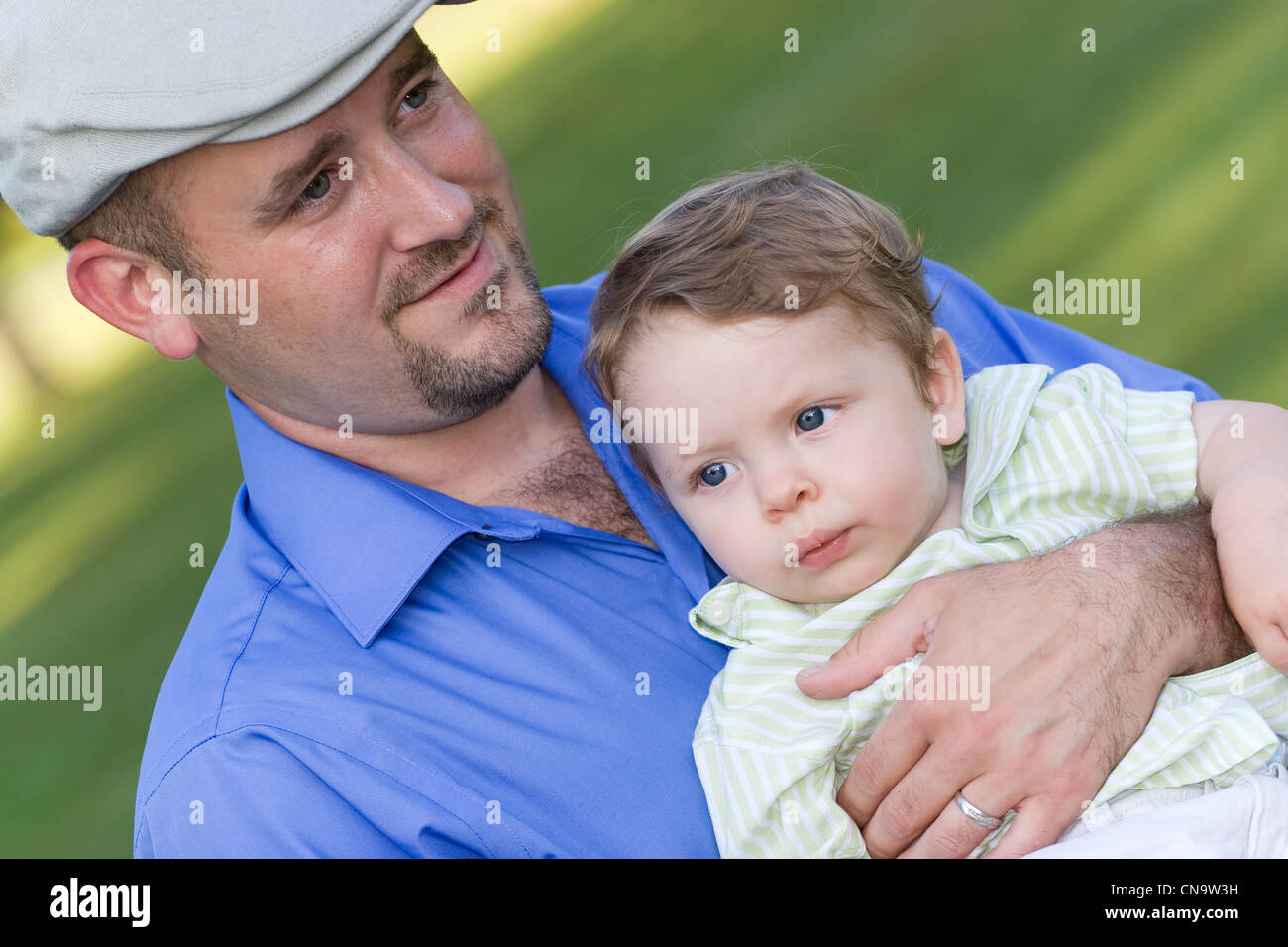 A proud young father holding his cute baby boy with a smile on his face ...