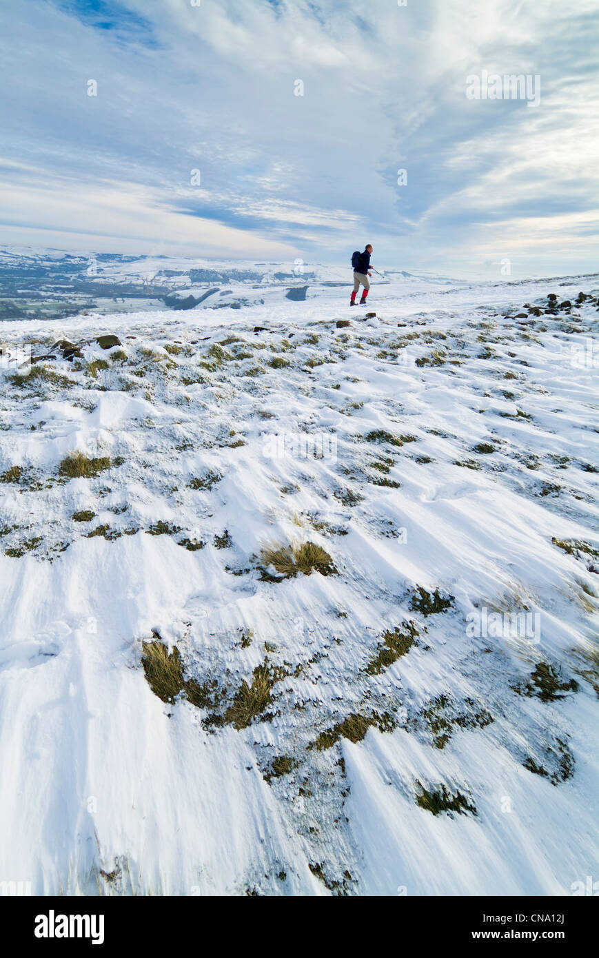 Hiker climbing Mam tor ridge in early snow Derbyshire Peak district ...