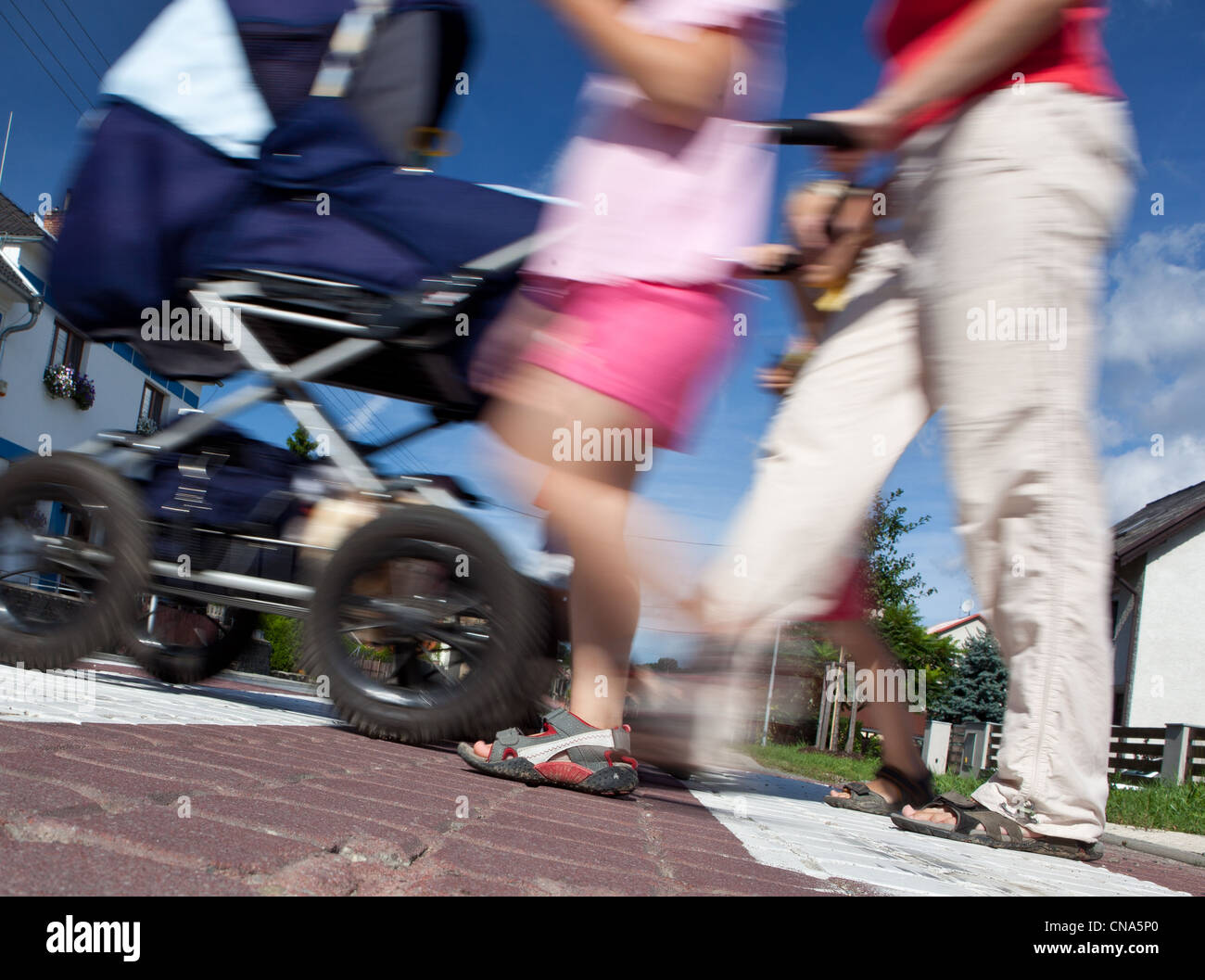 mother with small children and a pram crossing a street (motion blurred ...