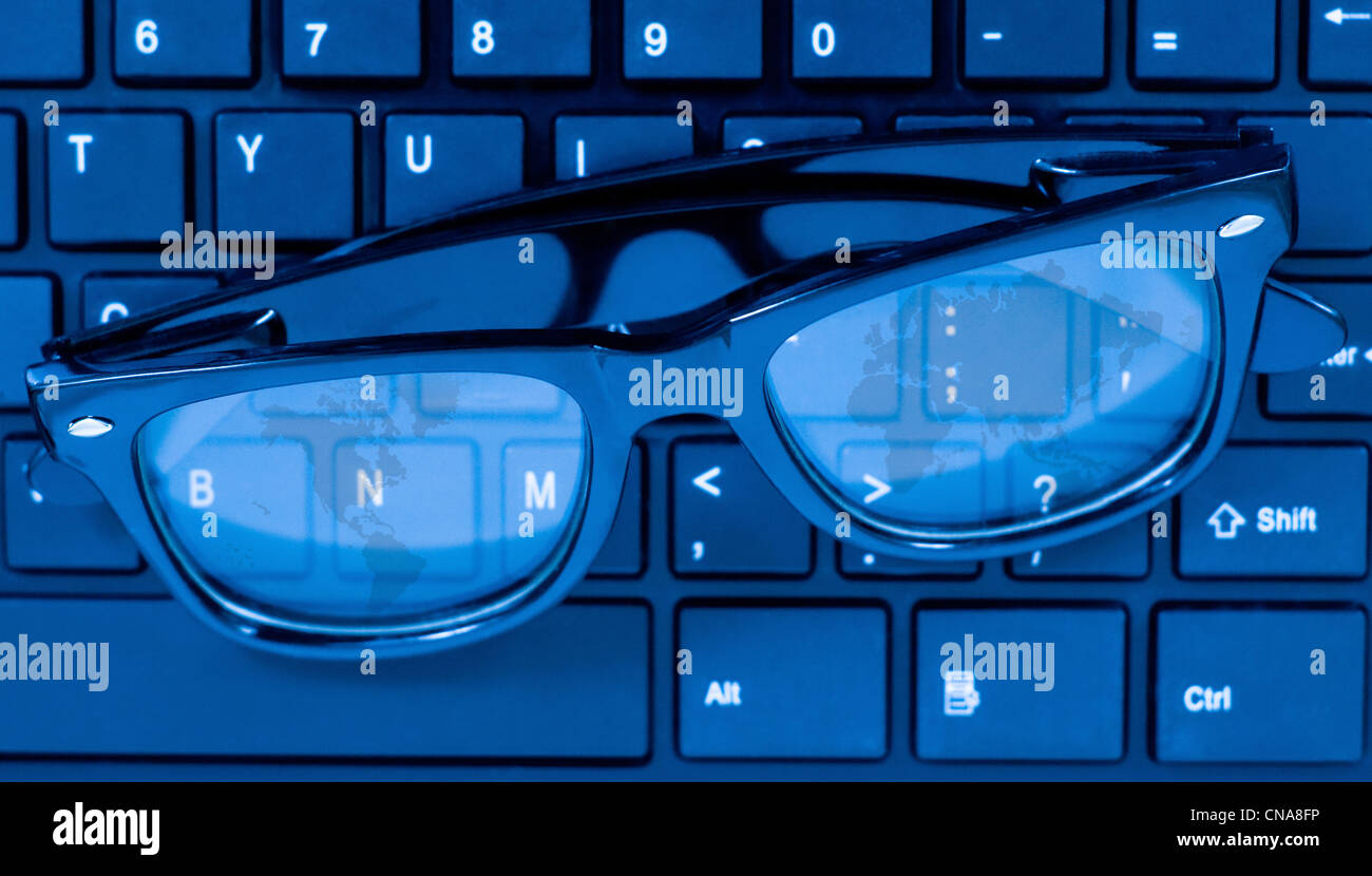Glasses on laptop computer keyboard with world map reflection on it ...