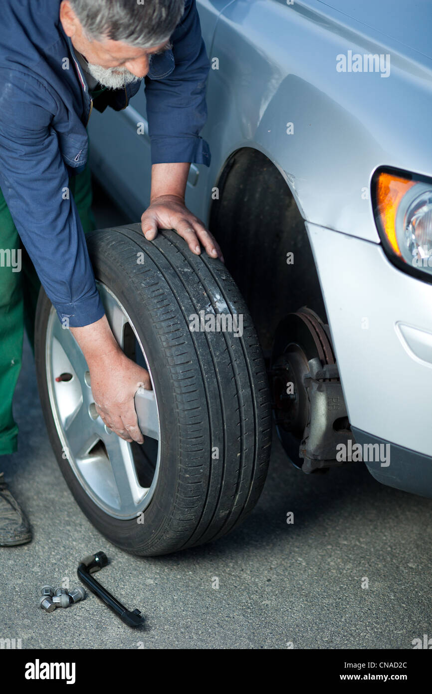 mechanic changing a wheel of a modern car (shallow DOF; color toned ...