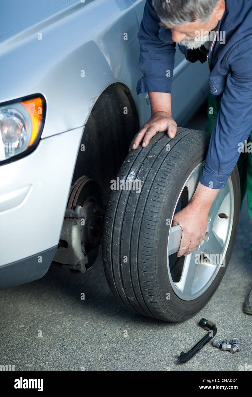 mechanic changing a wheel of a modern car (shallow DOF; color toned ...