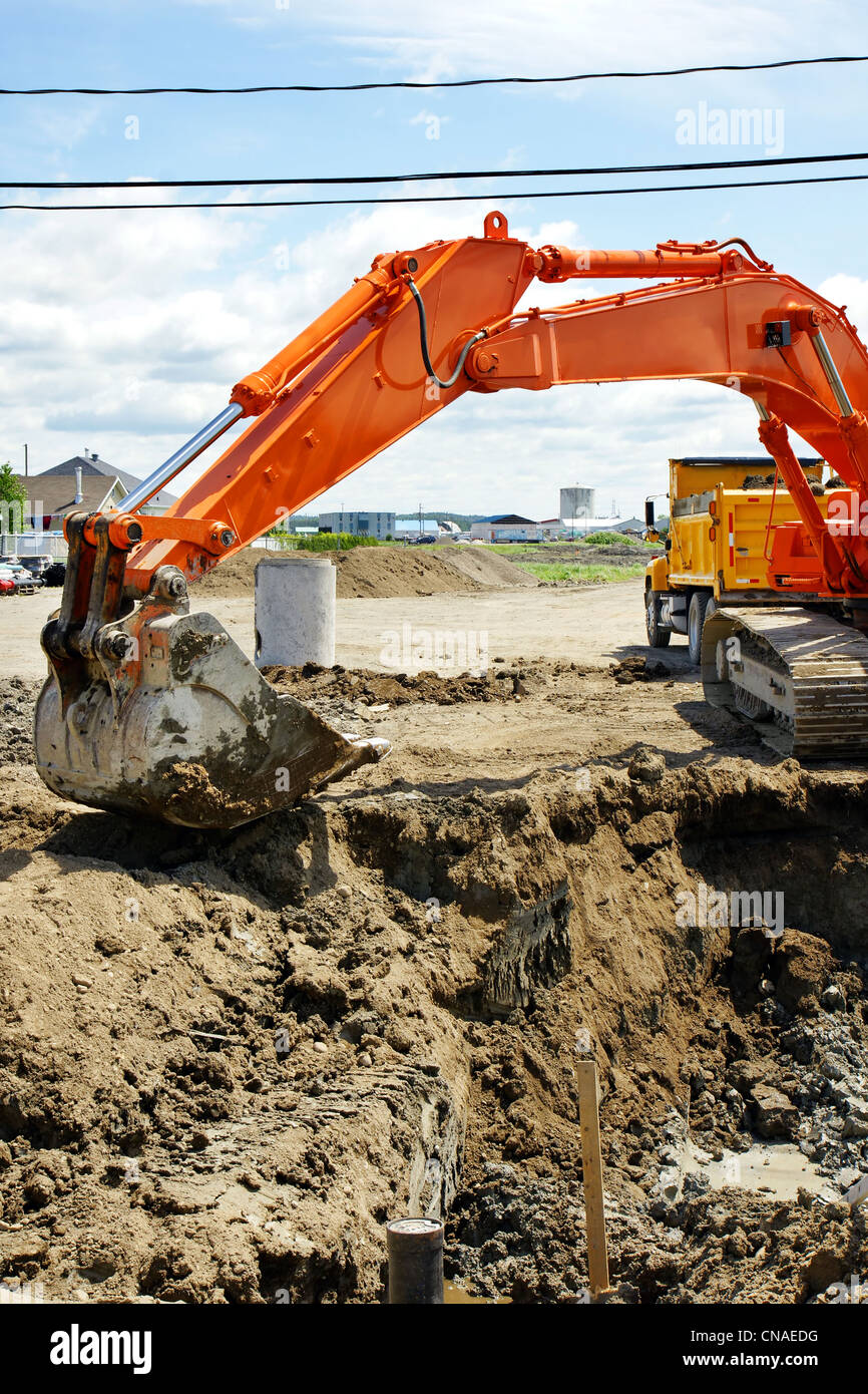 Mechanical digger digging large construction hole for sewage and water ...