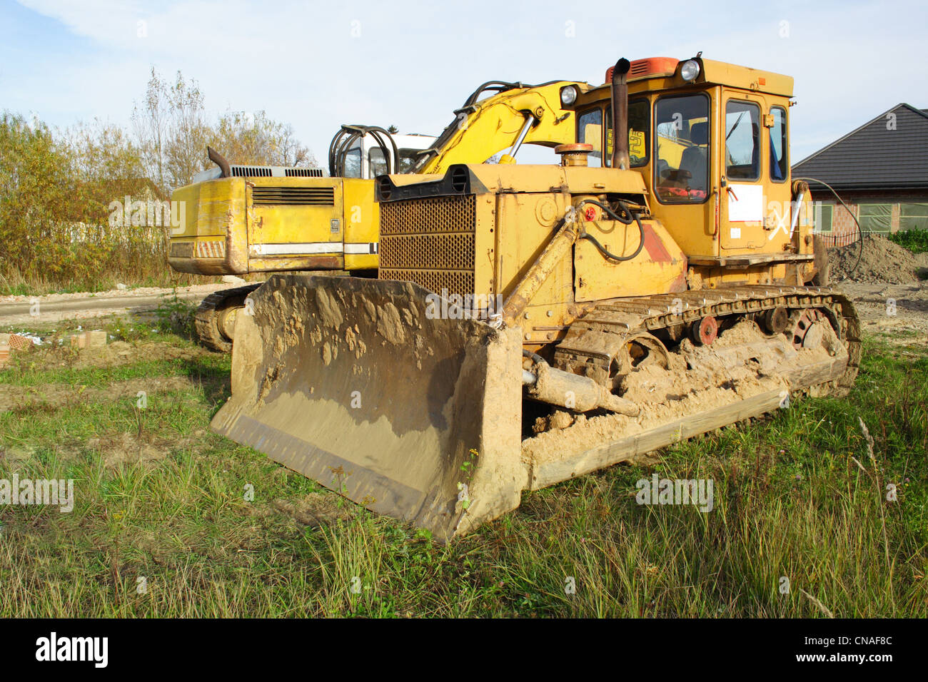 yellow bulldozer standing on the grass idly Stock Photo - Alamy