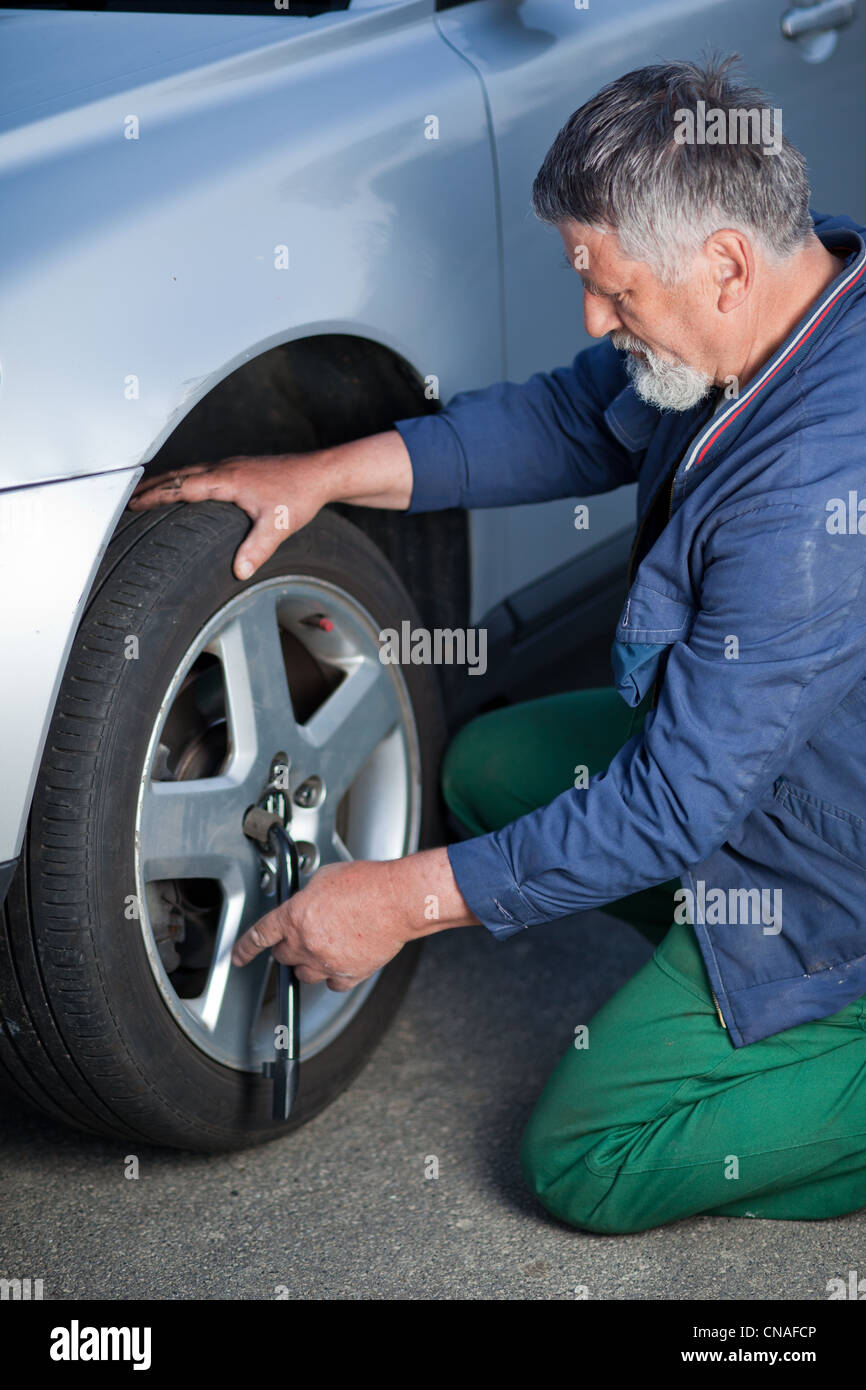 mechanic changing a wheel of a modern car (shallow DOF; color toned ...