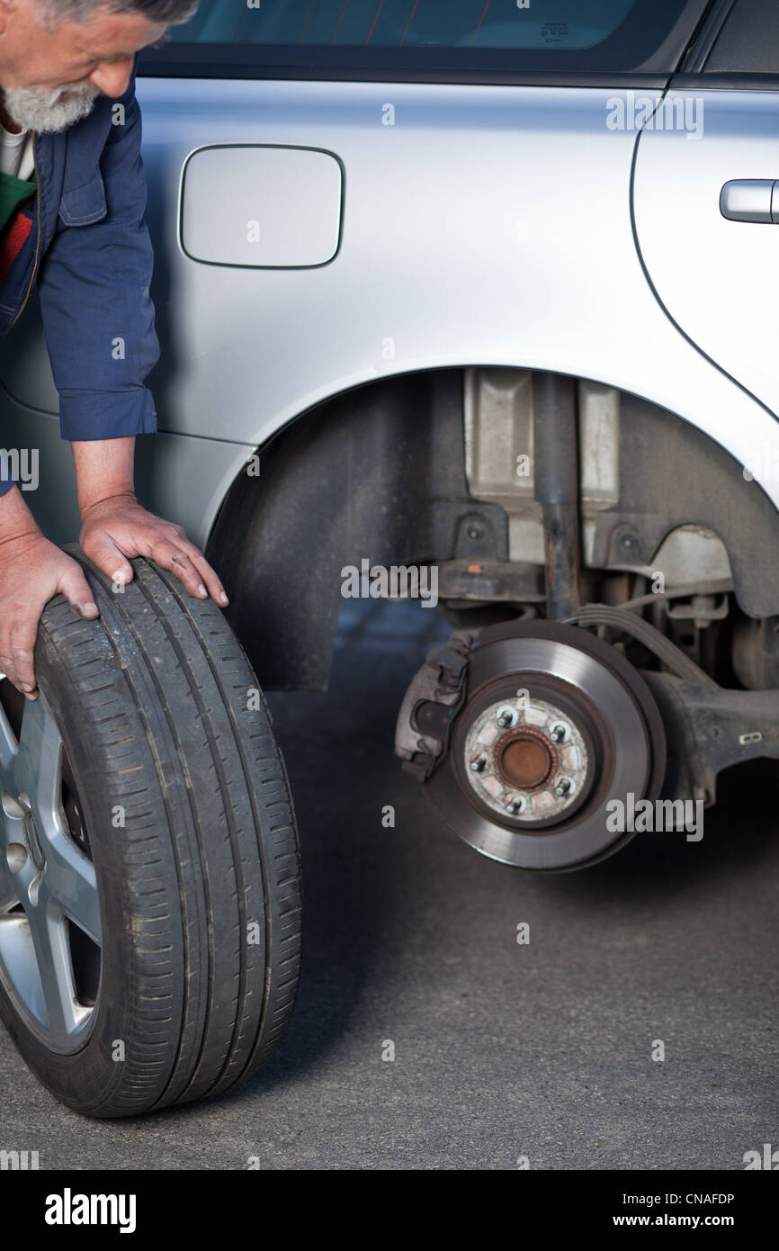 mechanic changing a wheel of a modern car (shallow DOF; color toned ...