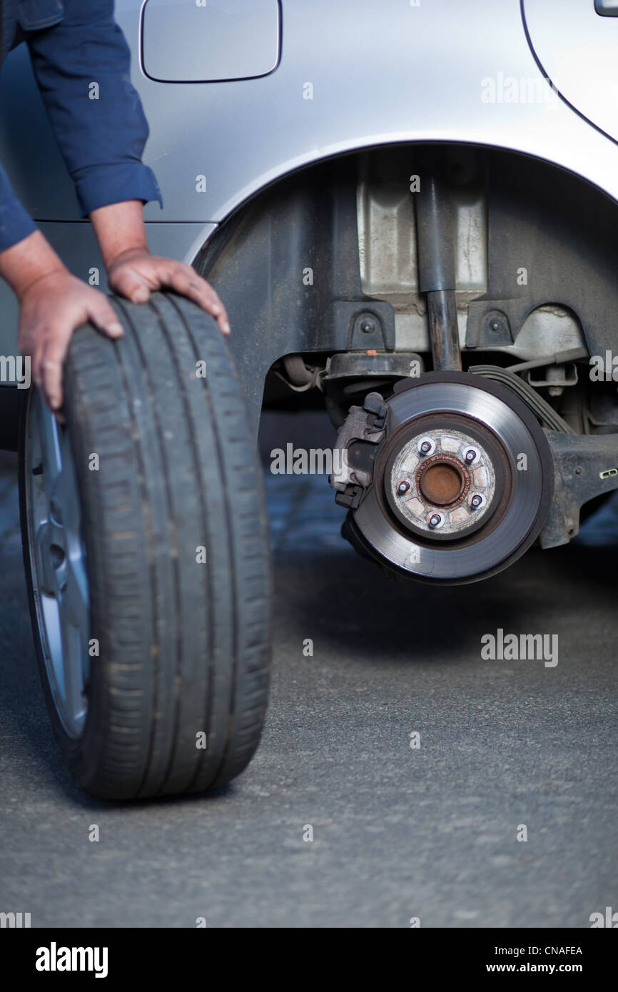 mechanic changing a wheel of a modern car (shallow DOF; color toned ...
