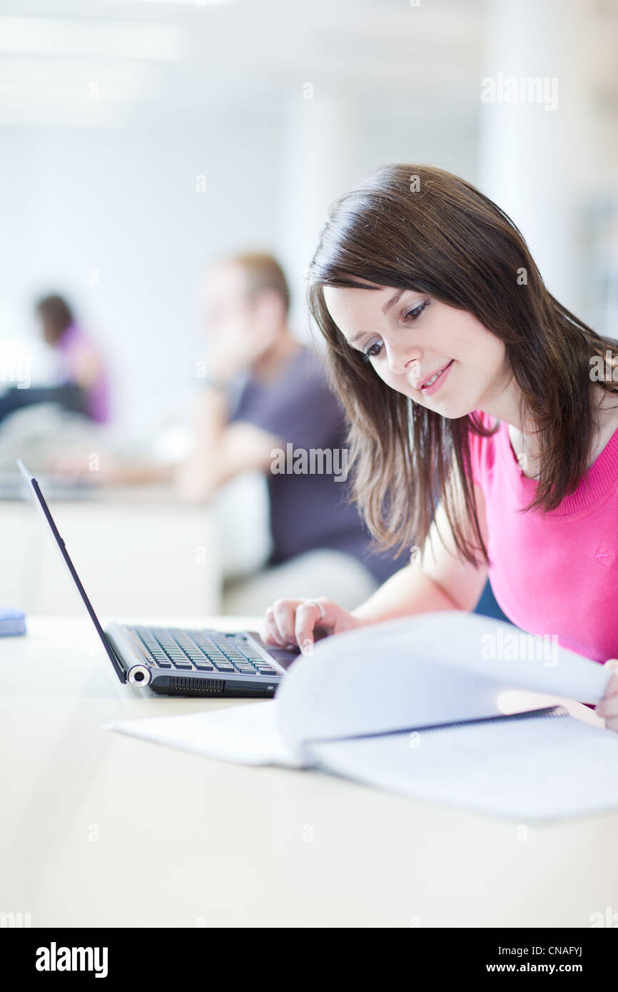 in the library - pretty female student with laptop and books working in ...