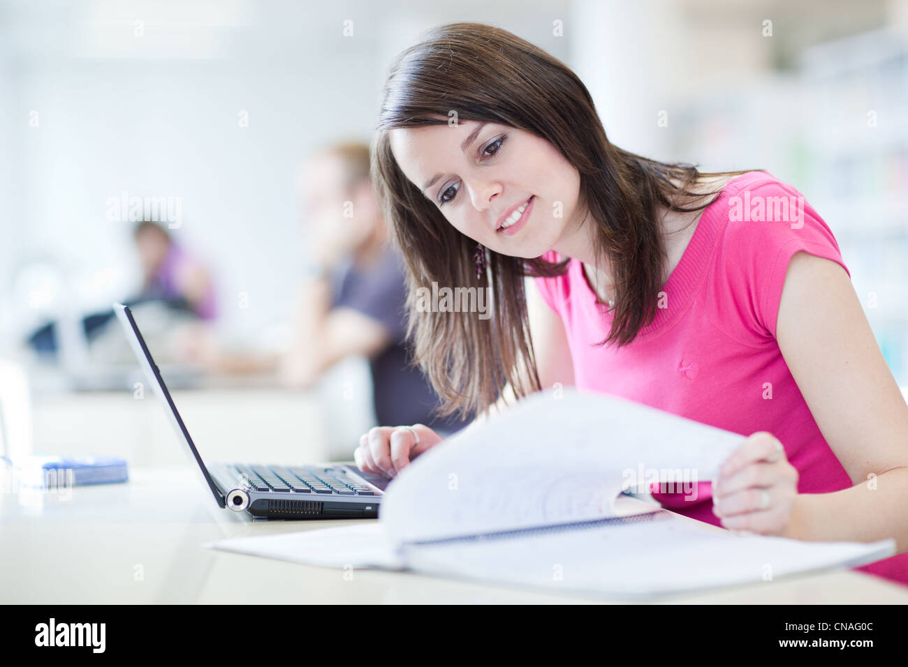 in the library - pretty female student with laptop and books working in ...