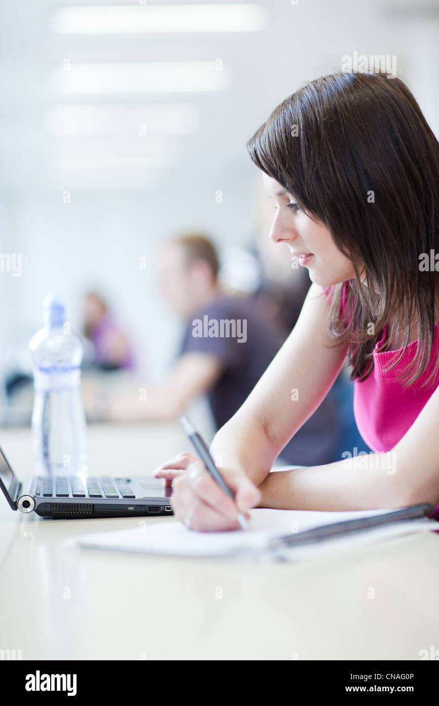 in the library - pretty female student with laptop and books working in ...