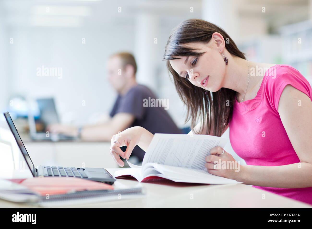 in the library - pretty female student with laptop and books working in ...