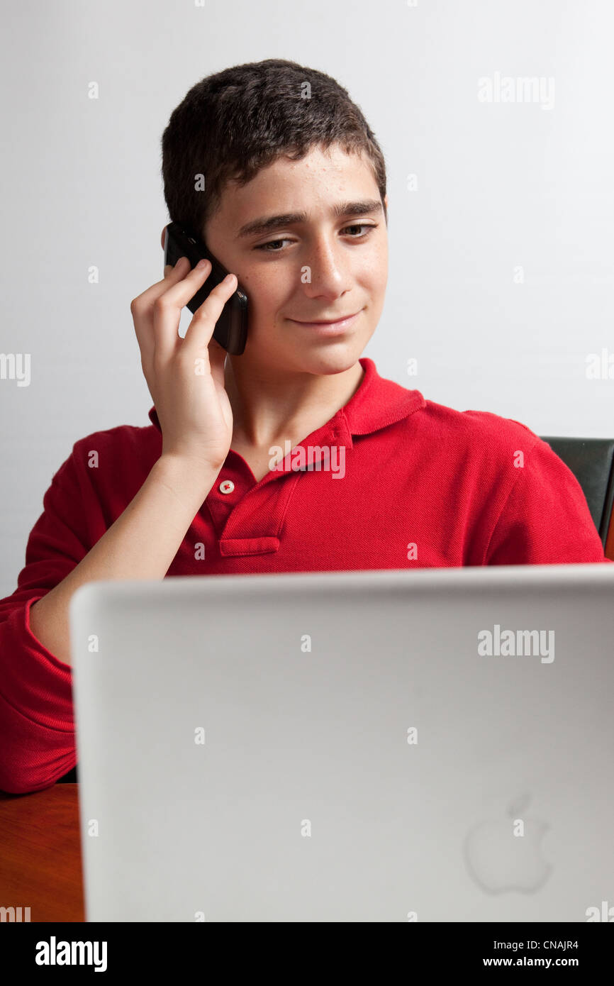 Teenager boy using laptop computer whilst using a smartphone Stock ...