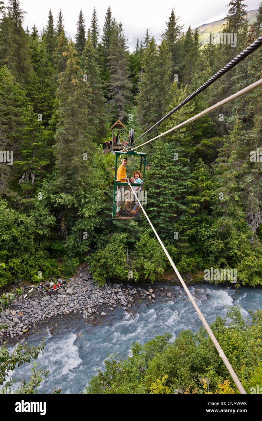 A family rides across Winner Creek in the hand tram near Girdwood ...