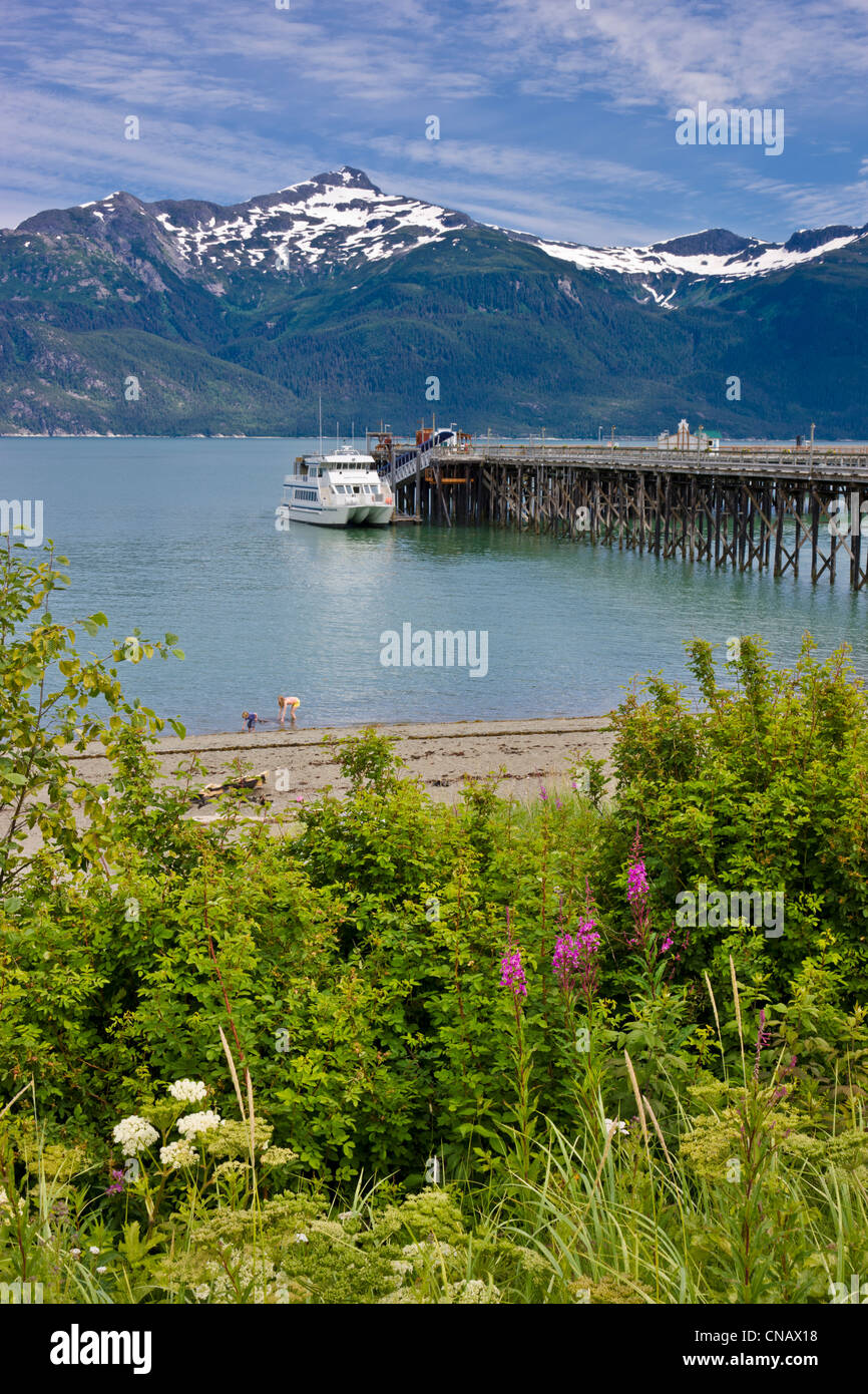 Tour boat moored at a dock at Portage Cove beach with Mount Villard in ...