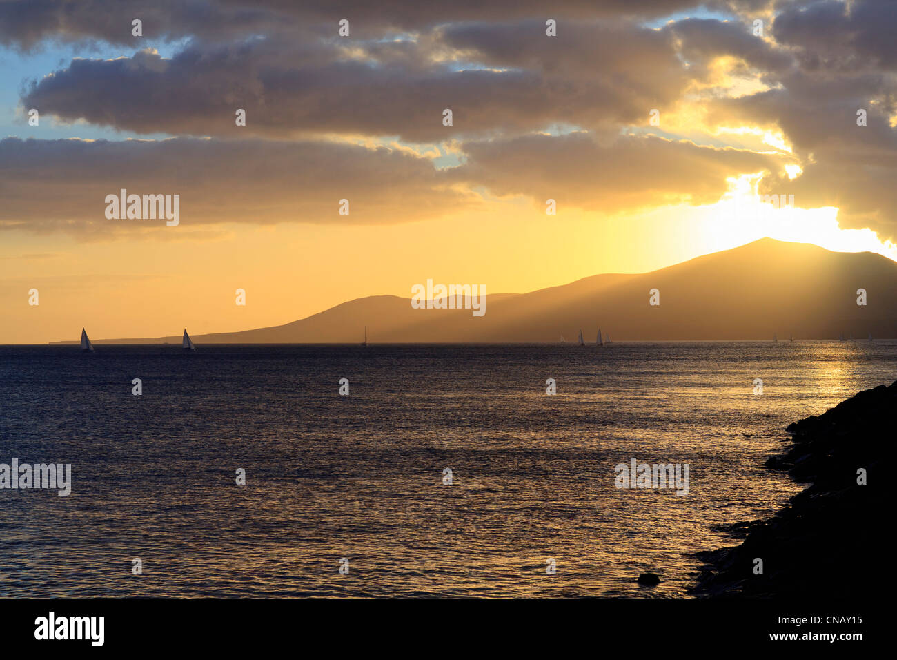 Sun setting over mountains and water Stock Photo - Alamy