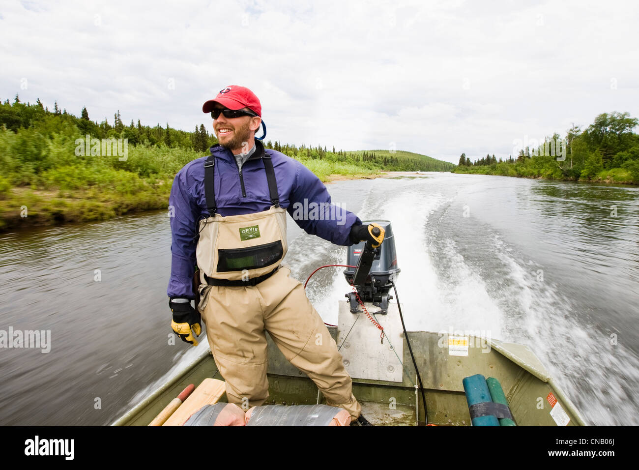 Sportfishing guide drives powered skiff on the Koktuli River in the ...