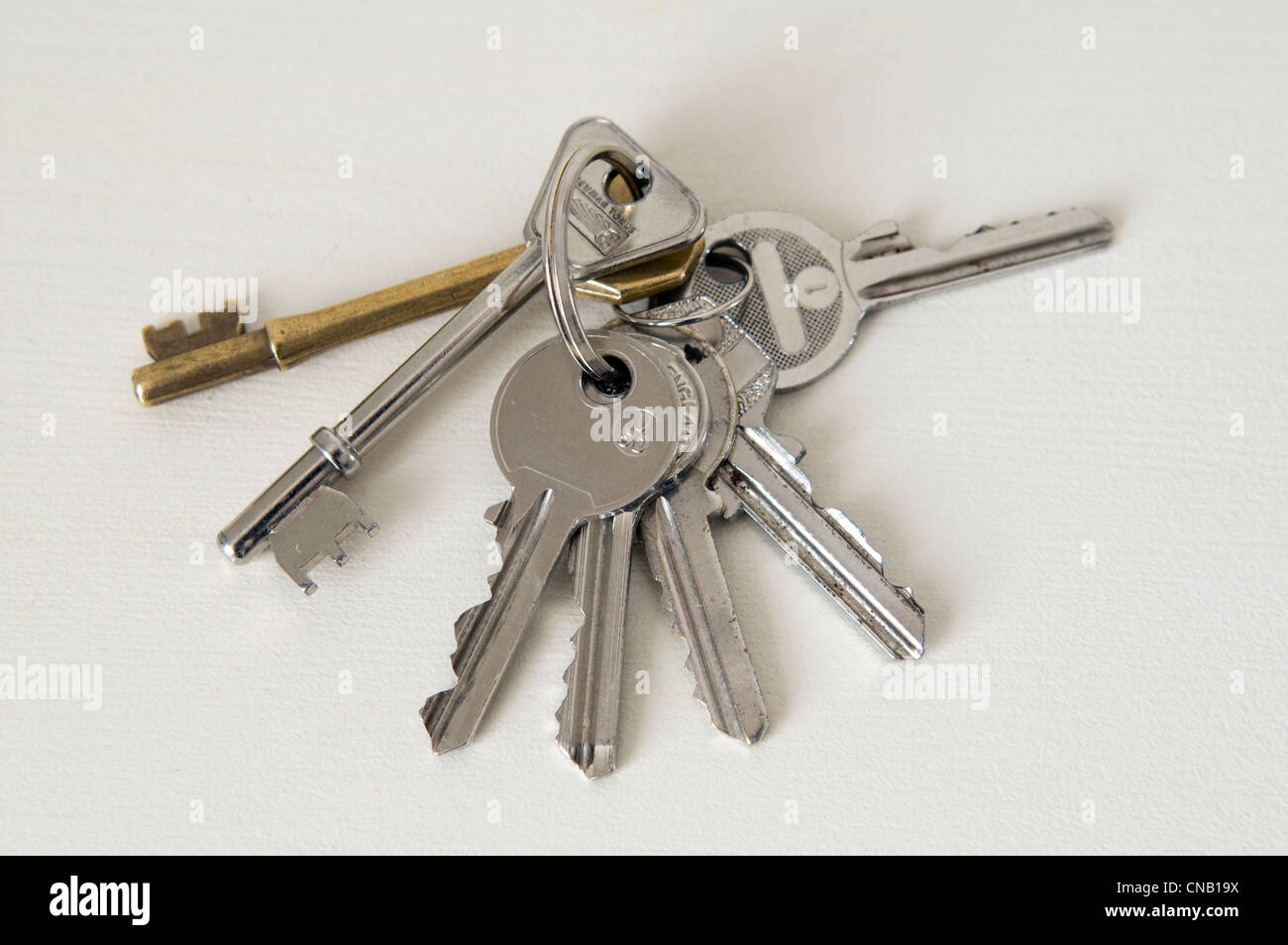 Bunch of various house keys taken against a light coloured wooden table ...