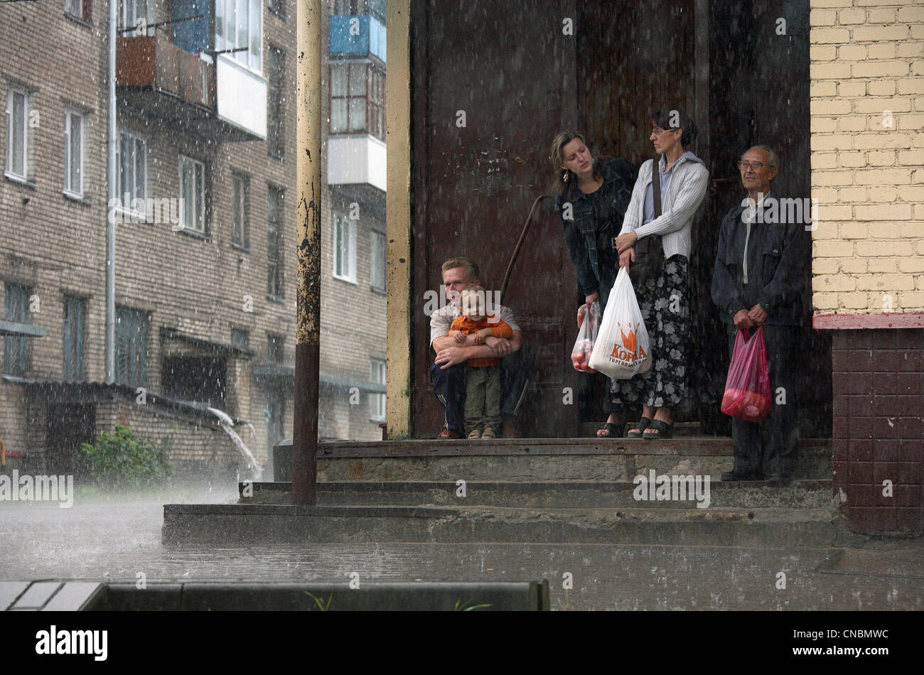 People hiding from the rain near an entrance to a building, Scucyn ...