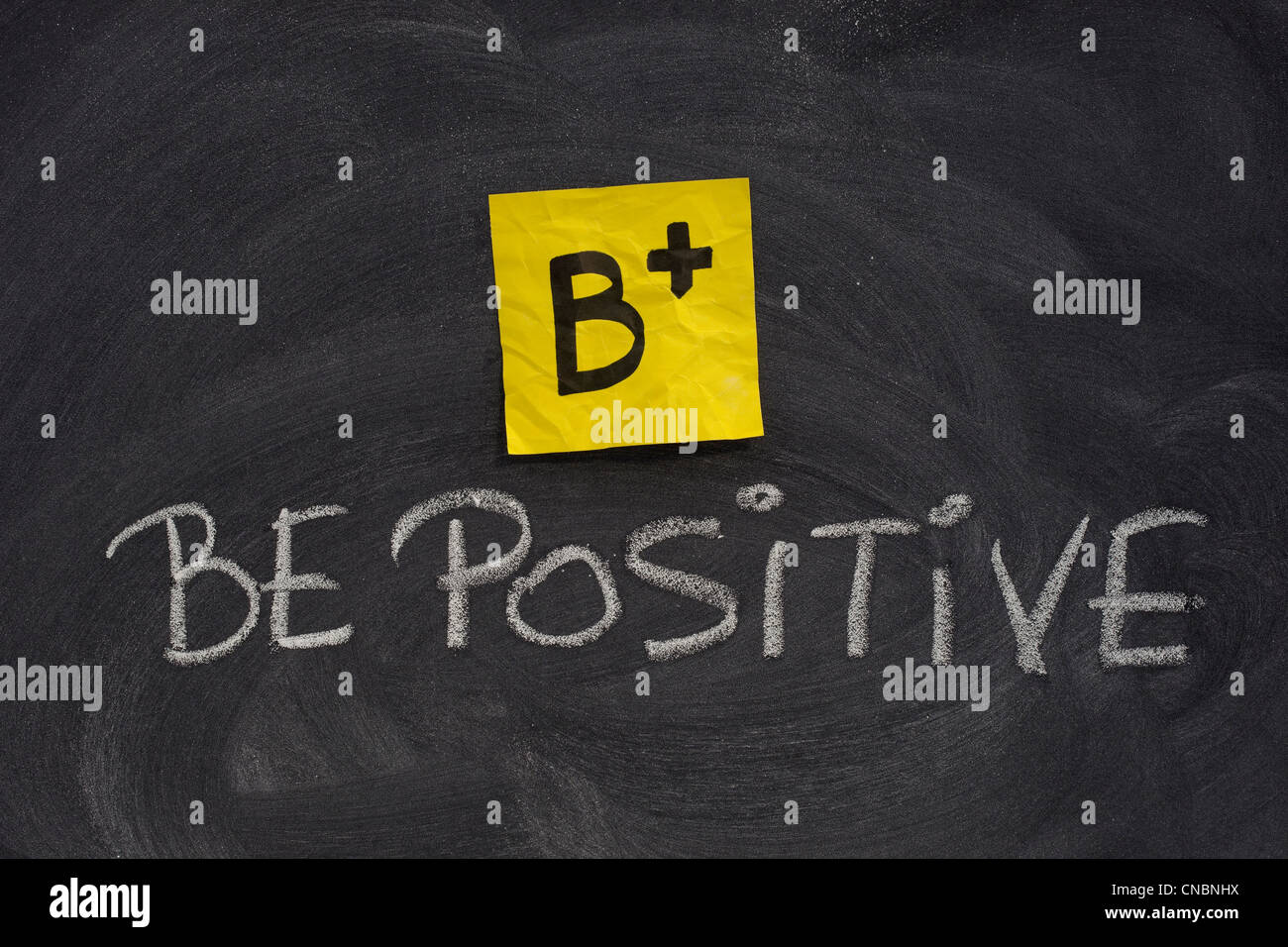 B+, be positive concept, yellow sticky note and white chalk handwriting ...