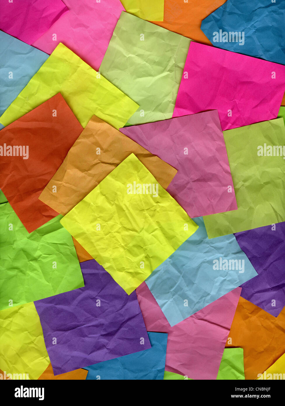 blank yellow sticky note on top of background of crumpled colorful ...