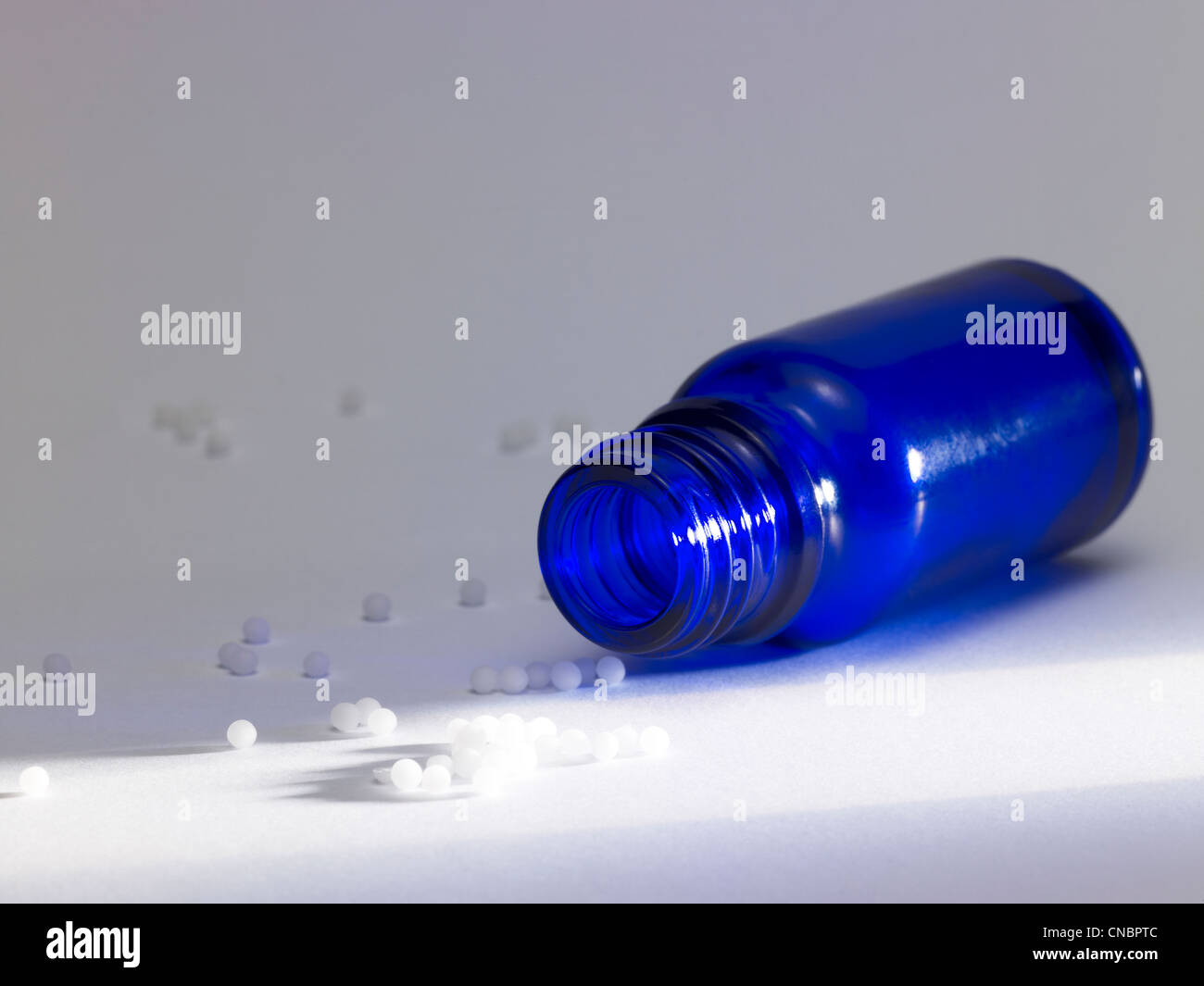 a open small blue bottle with globules around Stock Photo - Alamy