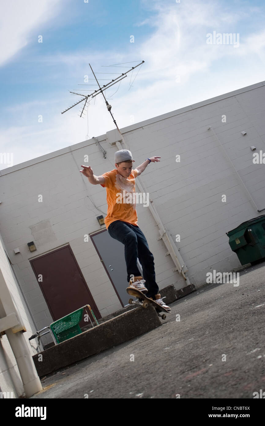 Portrait of a young skateboarder performing a trick in an urban setting ...