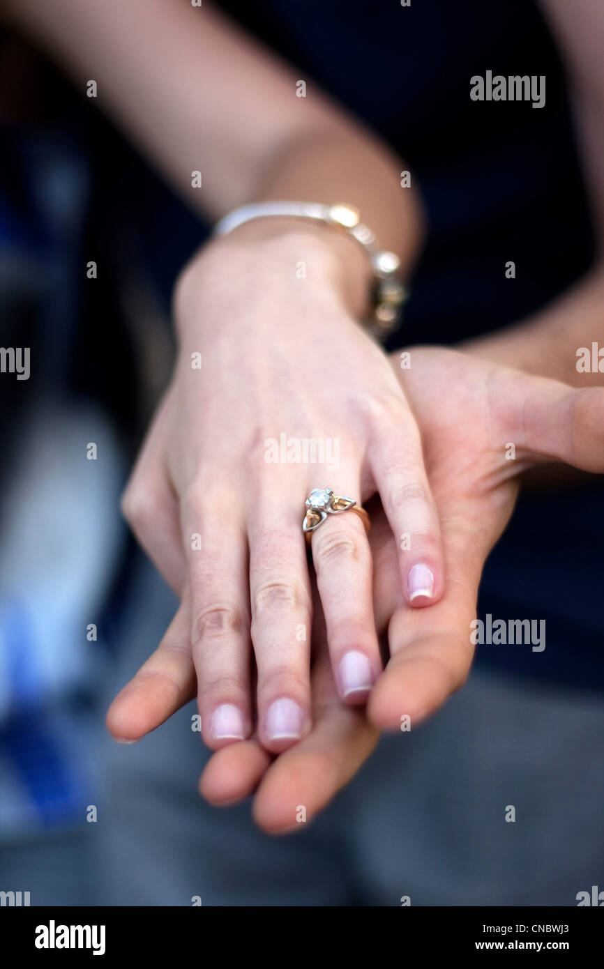 Close up of a young couples hands and diamond engagement ring with ...