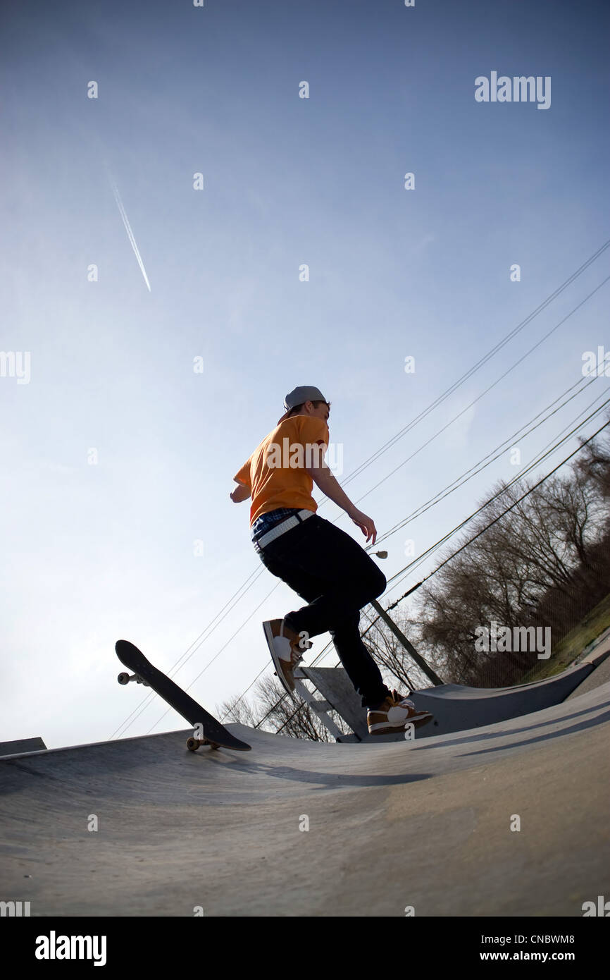 Portrait of a young skateboarder falling off of his board on a ramp at ...