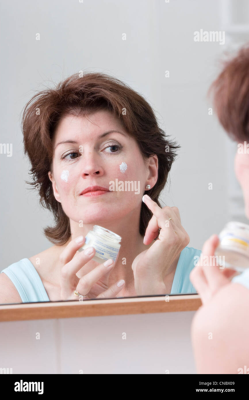 Woman putting skin lotion in mirror hi-res stock photography and images ...