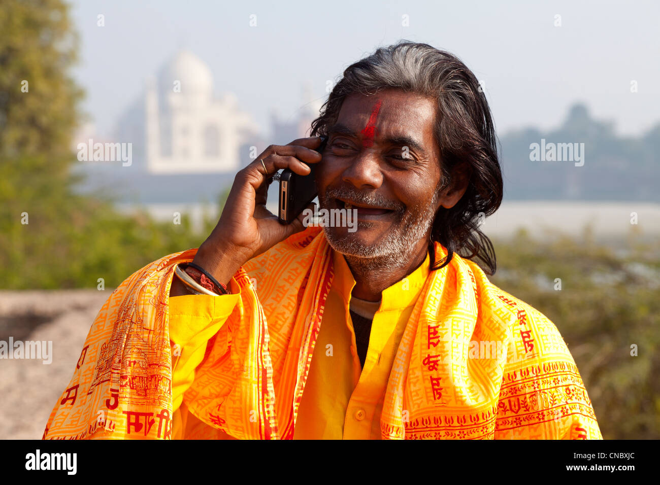 India, Uttar Pradesh, Agra, Holy Baba using smartphone with Taj mahal ...