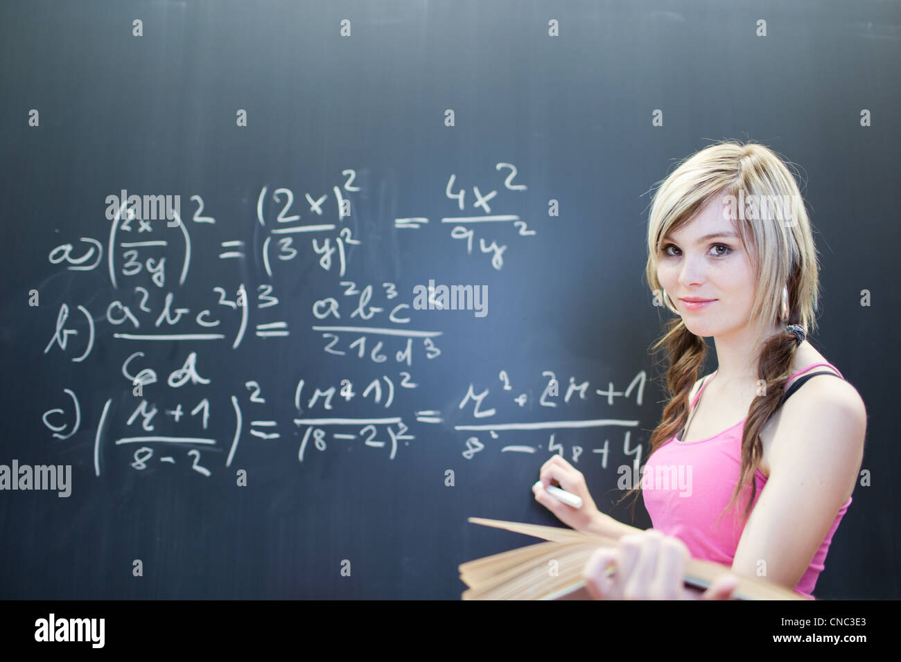pretty young college student writing on the chalkboard/blackboard ...