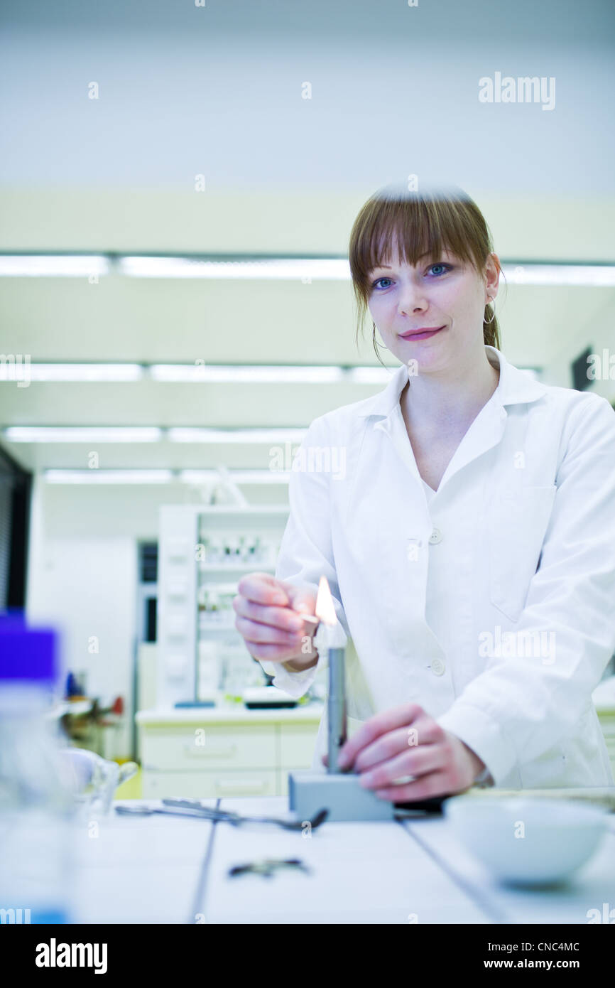 pretty, young female researcher lighting up a burner in a lab (shallow ...