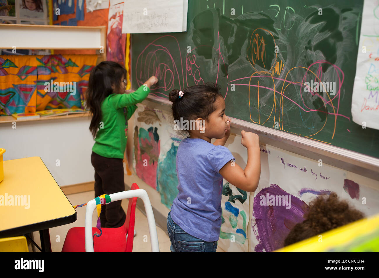 Two preschool girls drawing on the chalk board in the classroom Stock ...