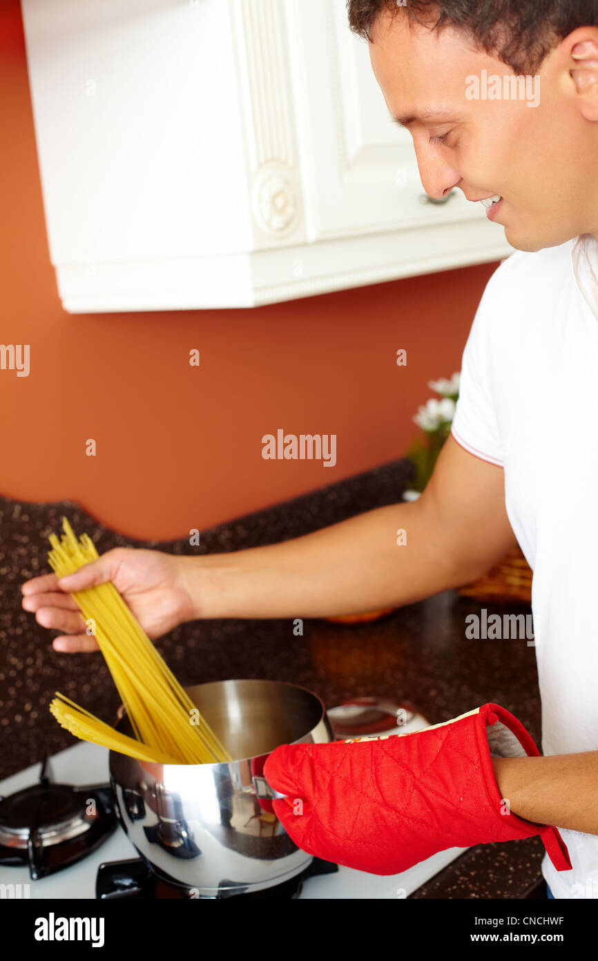 Portrait of young man cooking spaghetti in the kitchen Stock Photo - Alamy
