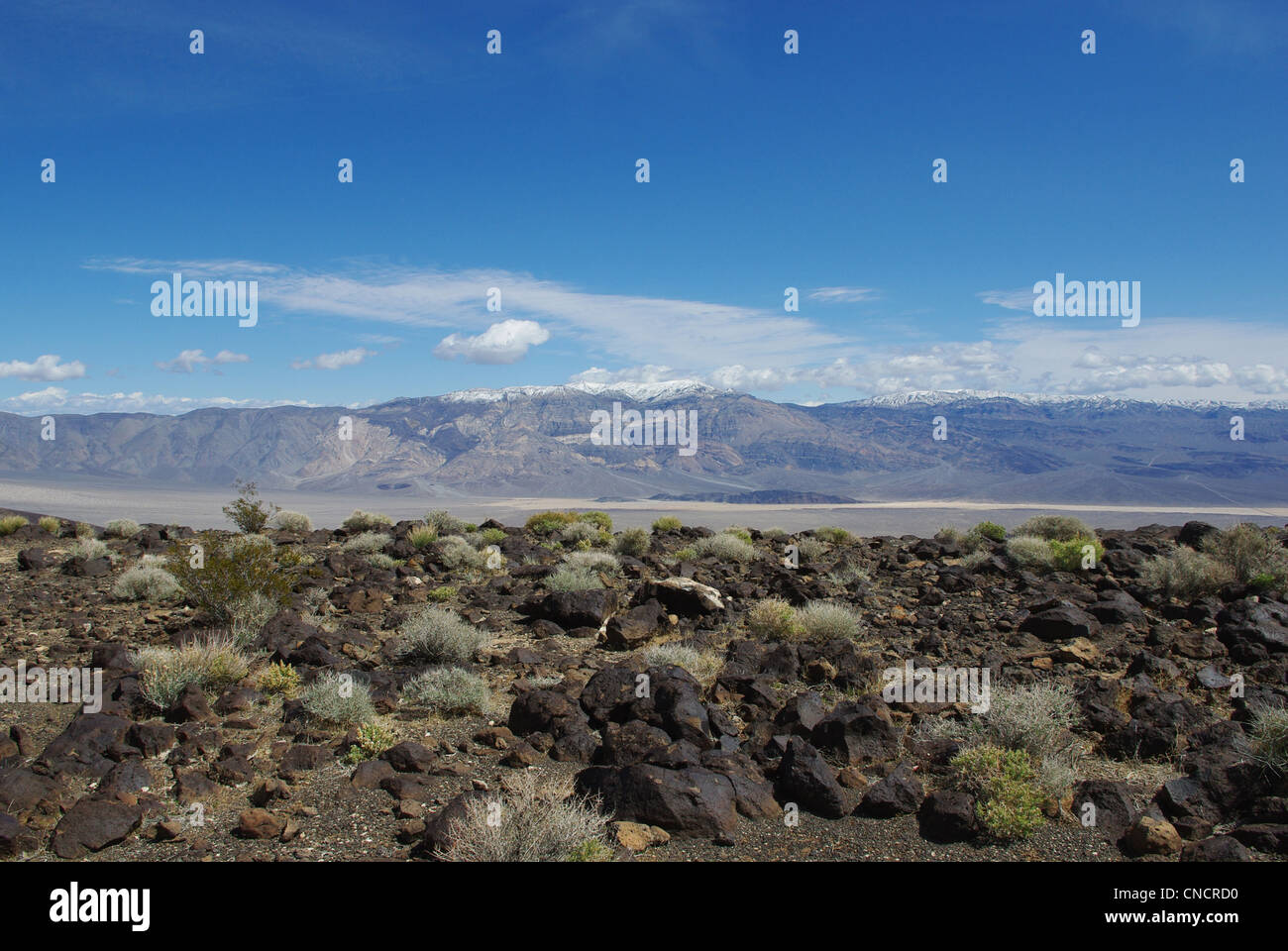 Black rocks above wide valley and high mountains near Death Valley ...