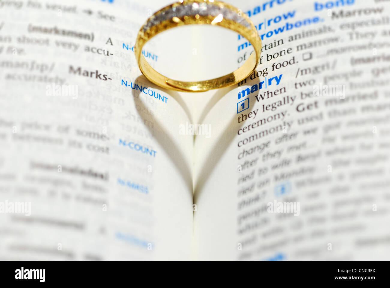 Wedding ring casting a heart onto a marry word Stock Photo - Alamy