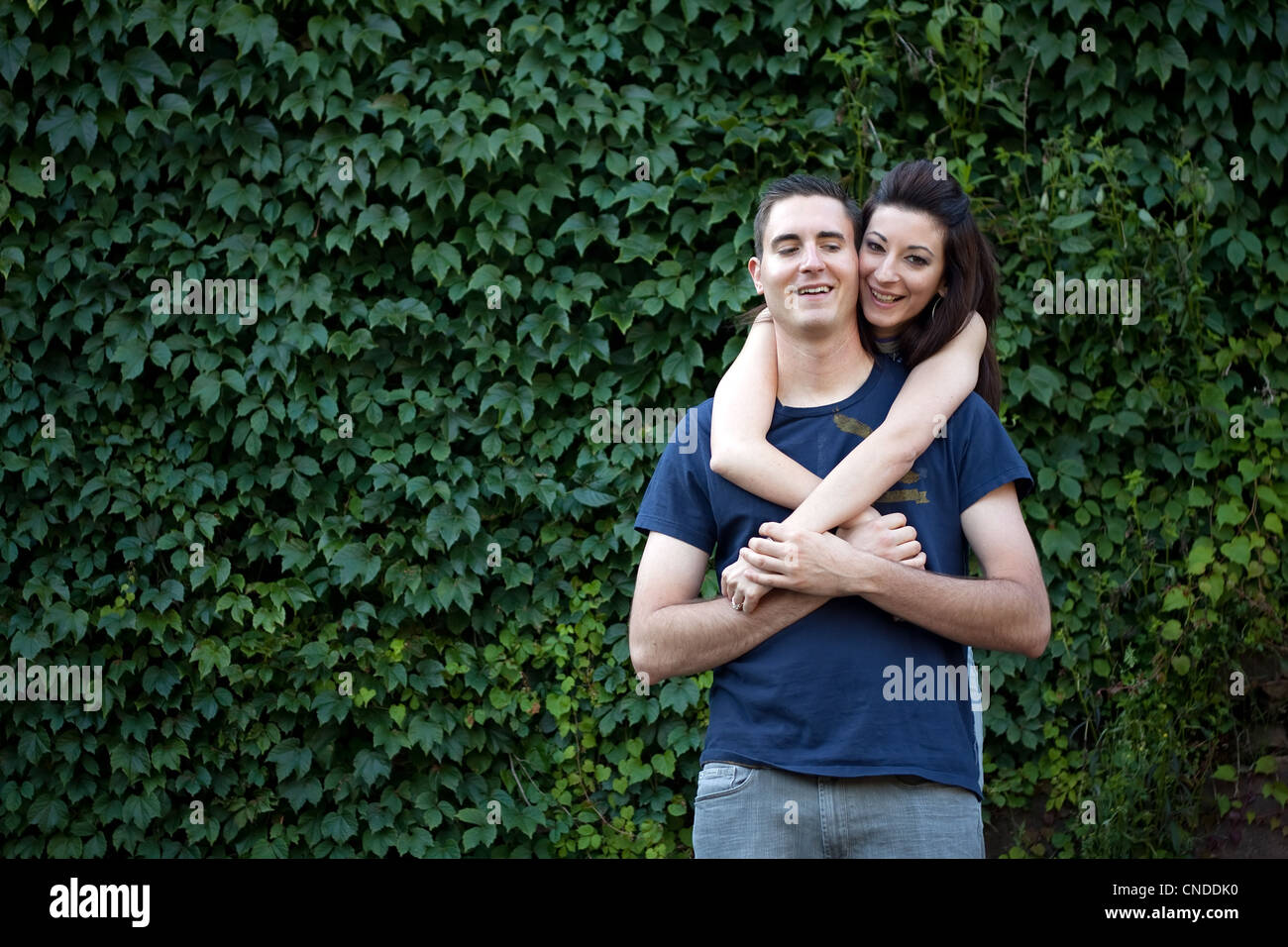 A happy young couple in their mid 20s together outdoors in front of ...