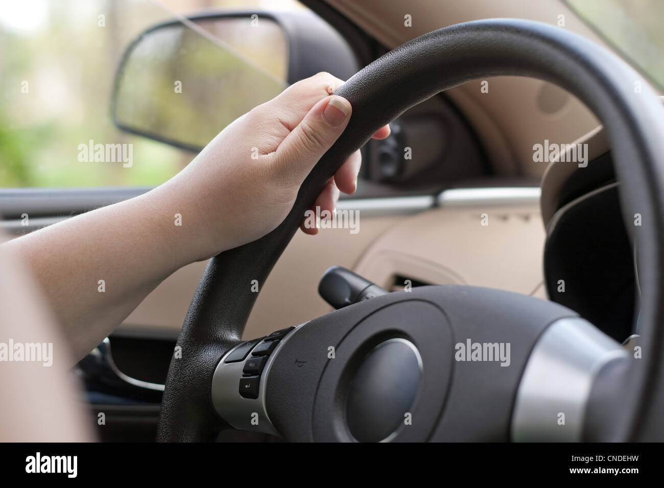 A woman holding the steering wheel of a car with one hand while driving ...