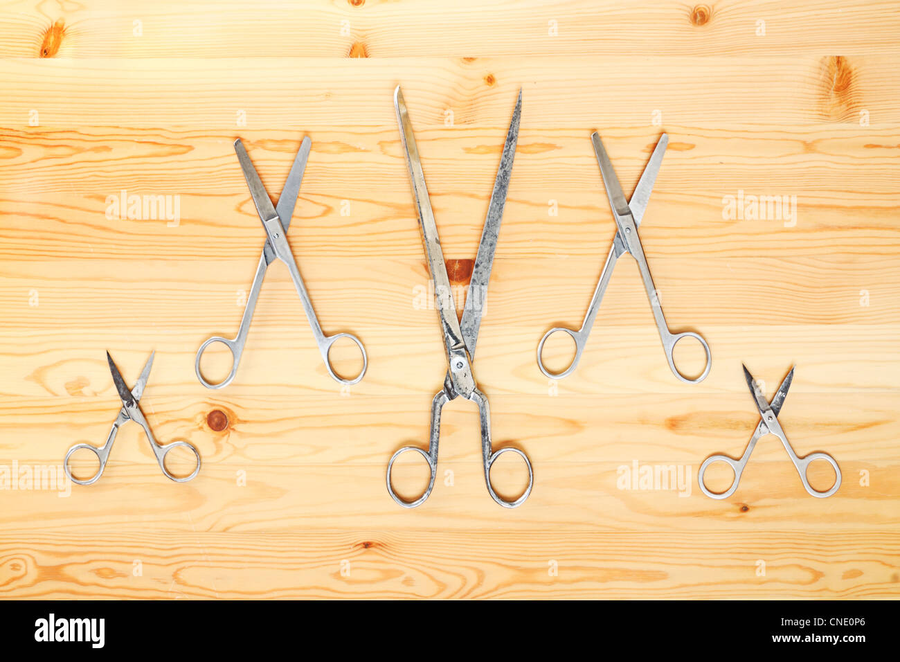 Different types of scissors lying on a wooden surface in the form XXXXX ...