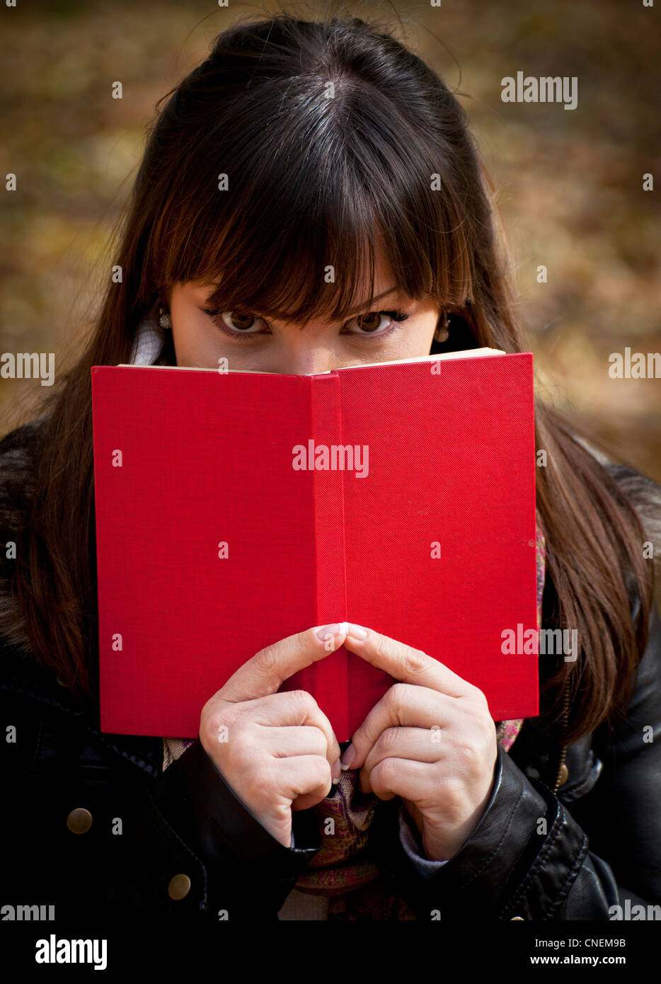 Beautiful girl hiding behind the book Stock Photo - Alamy