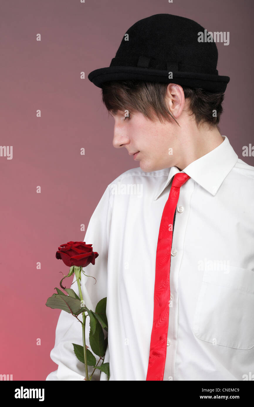 Young men with the red rose on colour background. Love and reflection ...