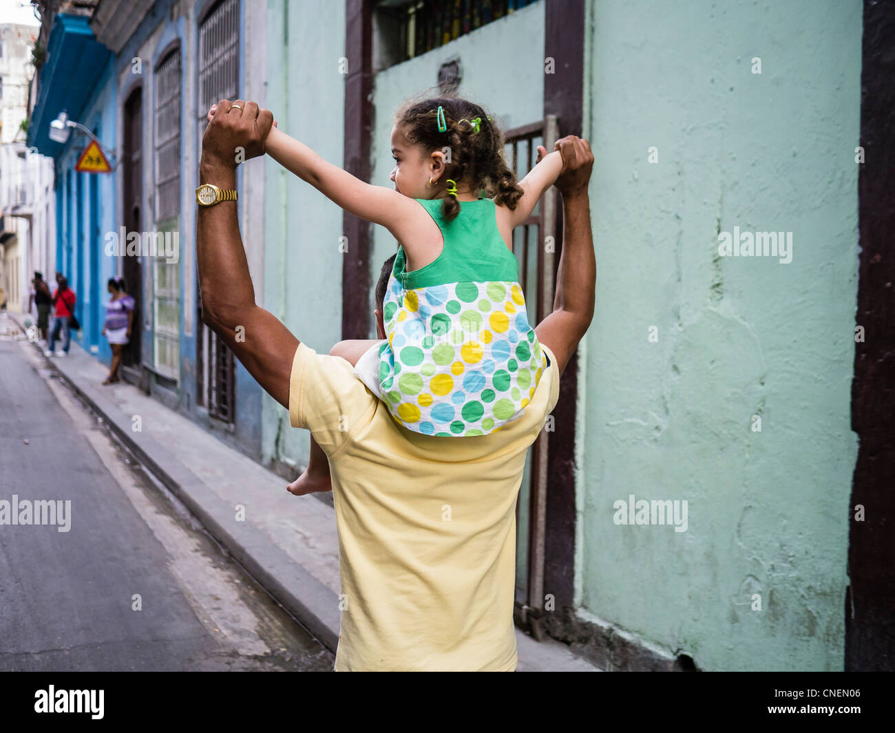 A Cuban father in Havana carries his young daughter on his shoulders ...
