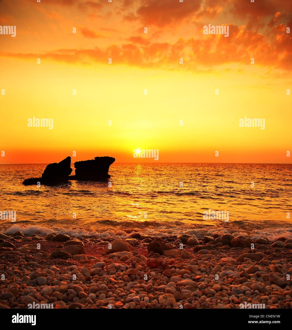 Beautiful warm sunset on the beach, seascape with calm ocean and rocks ...
