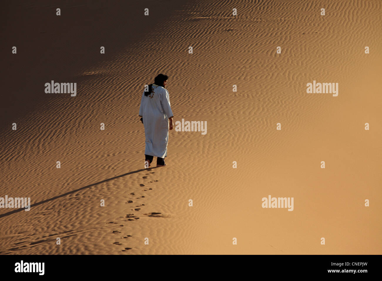 Moroccan Berber arab in traditional dress walking in the Chegaga dunes ...